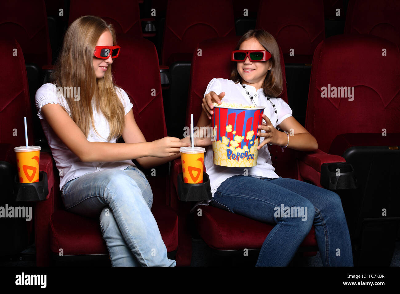 Two young girls watching movie in cinema Stock Photo - Alamy
