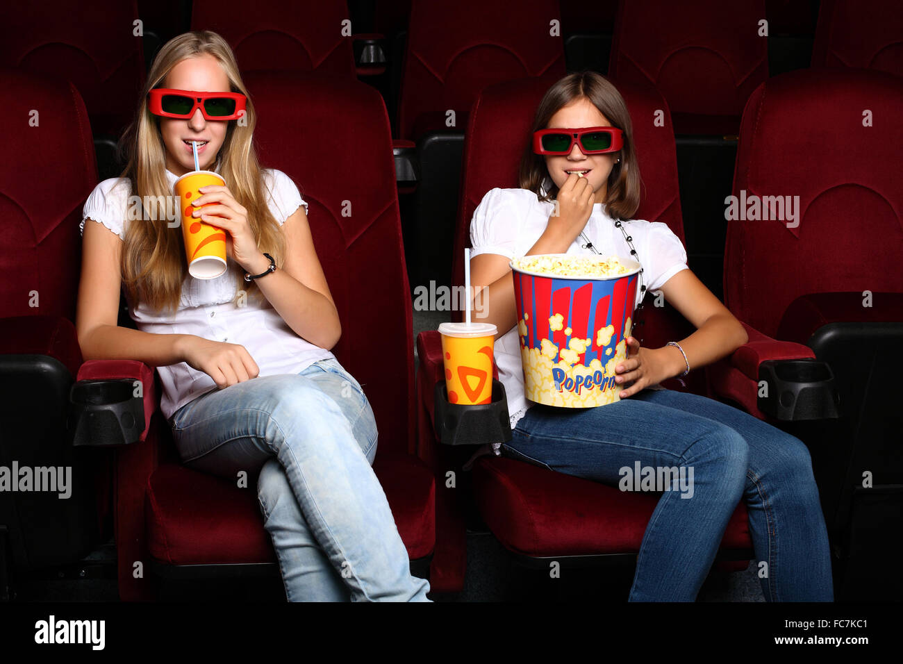 Two young girls watching movie in cinema Stock Photo - Alamy