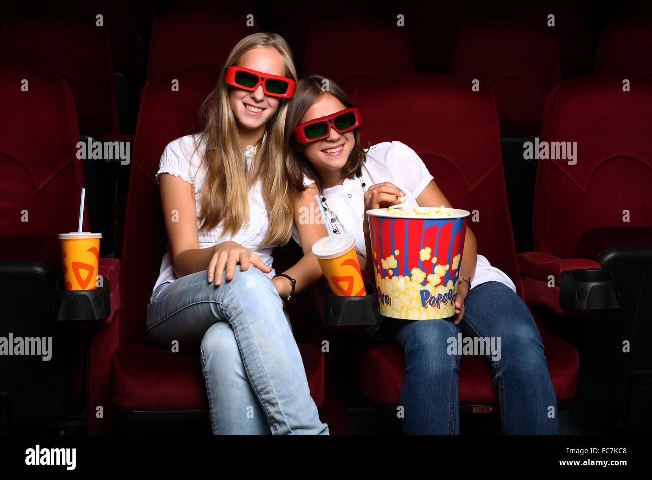 Two young girls watching movie in cinema Stock Photo - Alamy