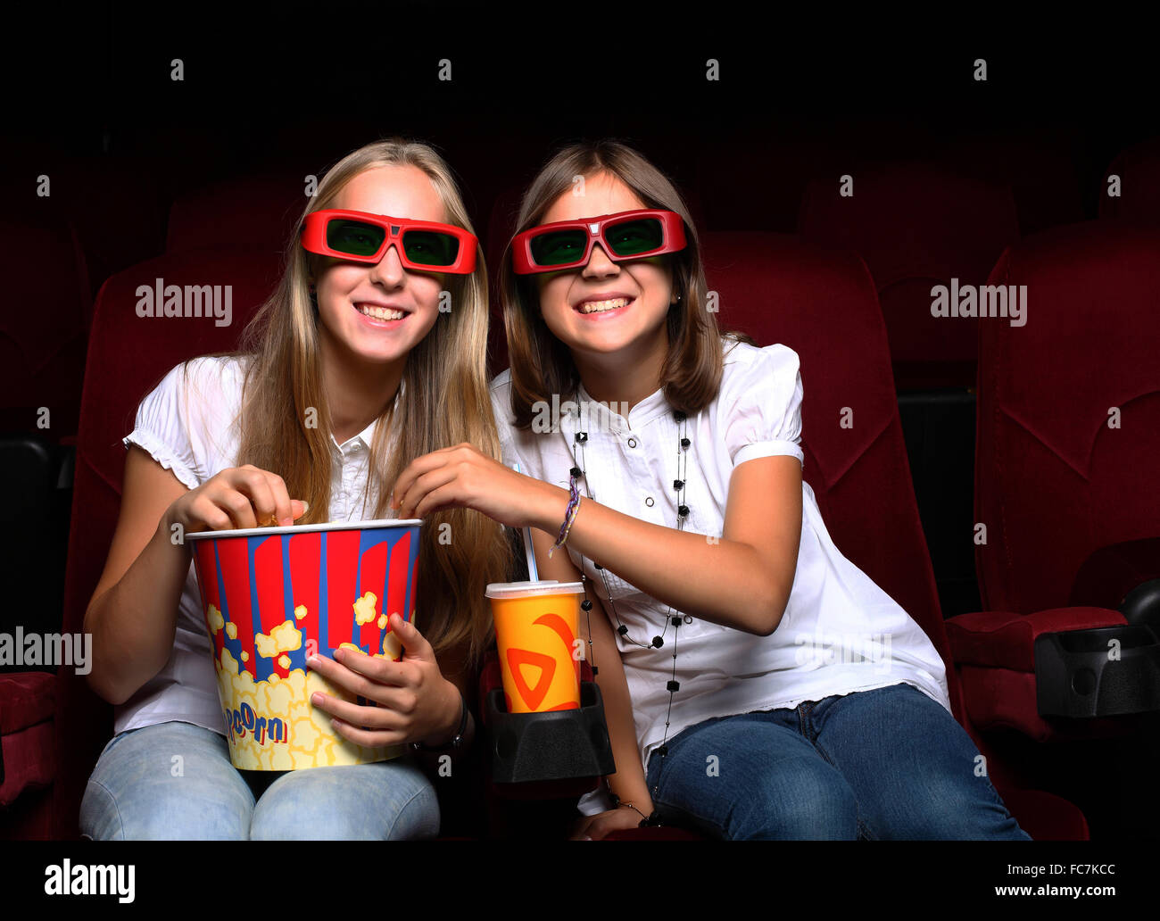 Two young girls watching movie in cinema Stock Photo - Alamy