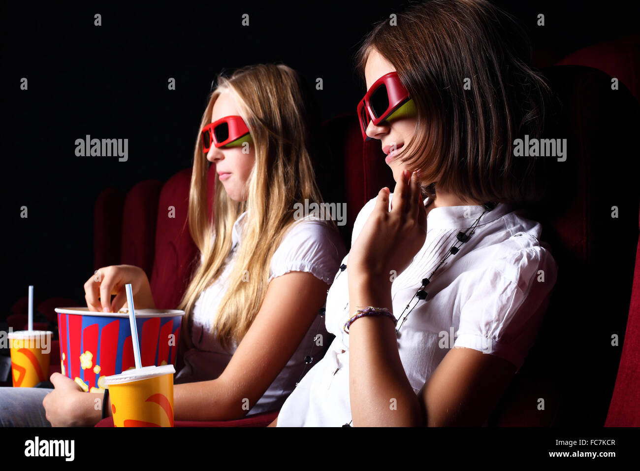 Two young girls watching movie in cinema Stock Photo - Alamy