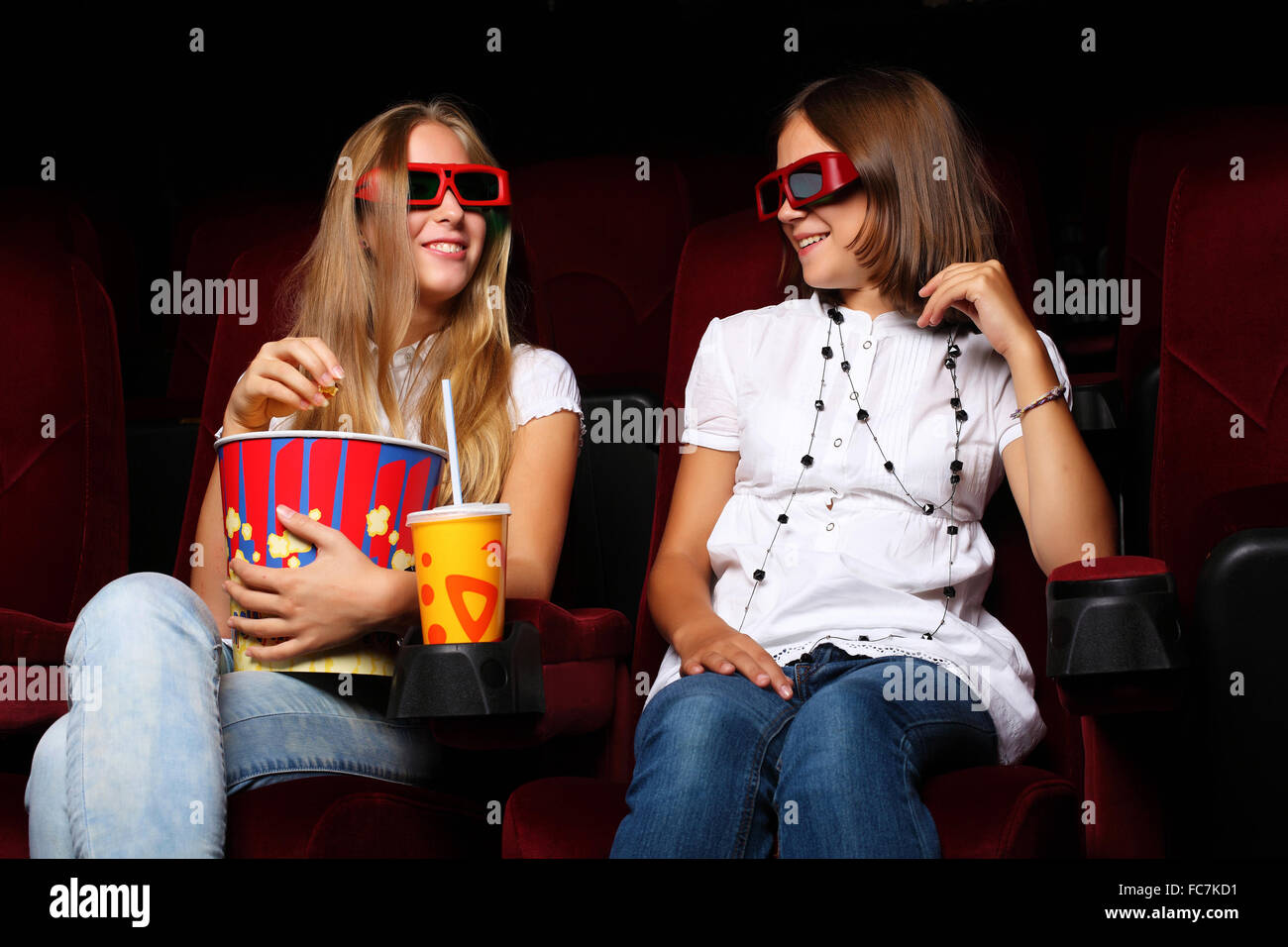 Two young girls watching movie in cinema Stock Photo - Alamy