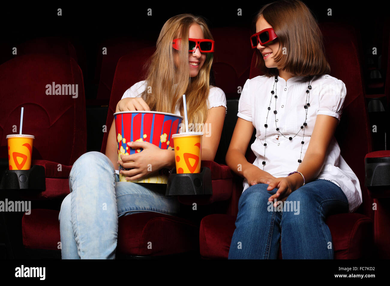 Two young girls watching movie in cinema Stock Photo - Alamy