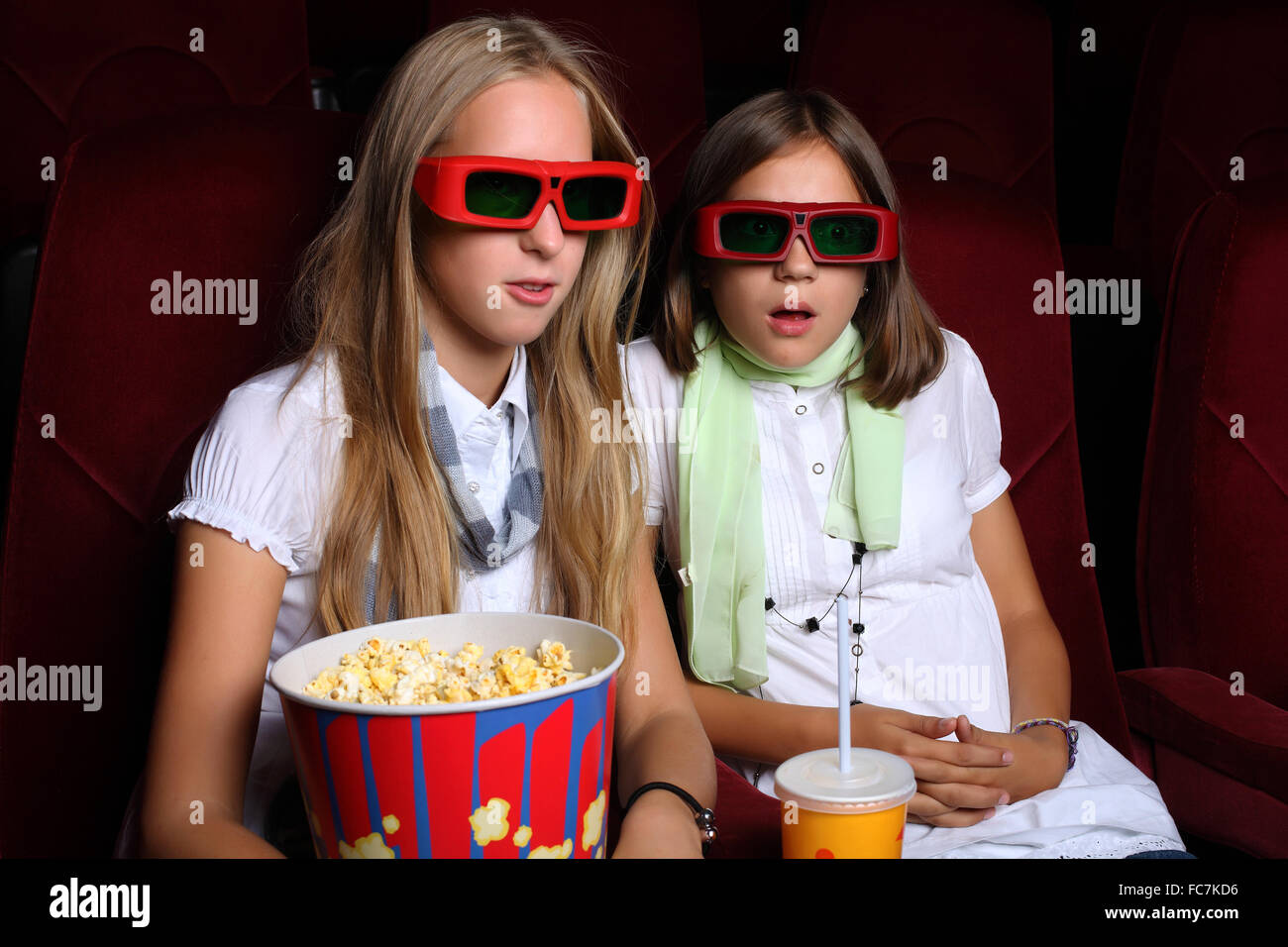 Two young girls watching movie in cinema Stock Photo - Alamy