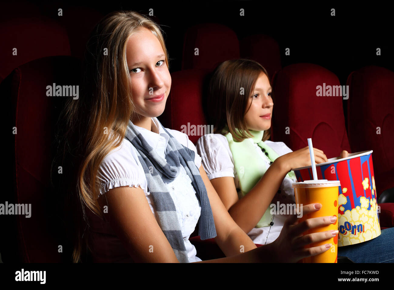 Two young girls watching movie in cinema Stock Photo - Alamy
