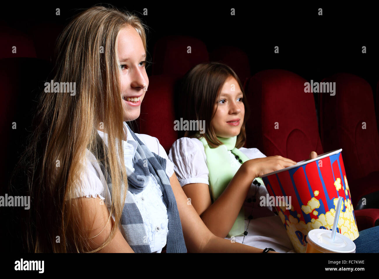 Two young girls watching movie in cinema Stock Photo - Alamy