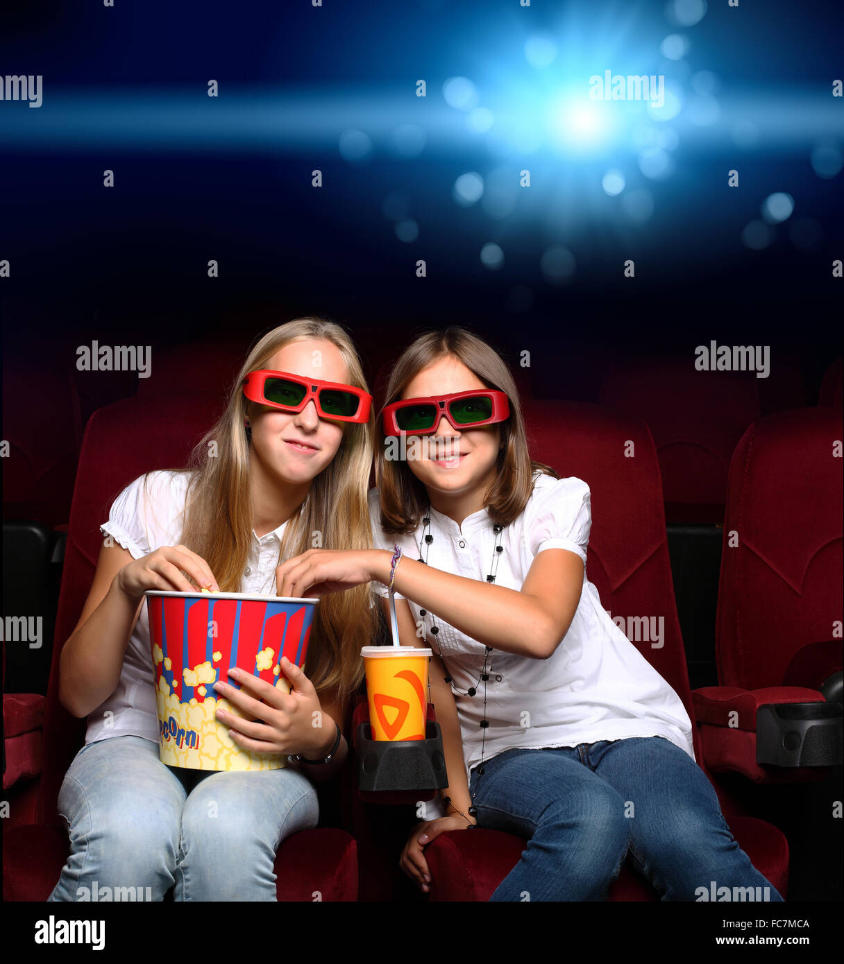 Two young girls watching movie in cinema Stock Photo - Alamy