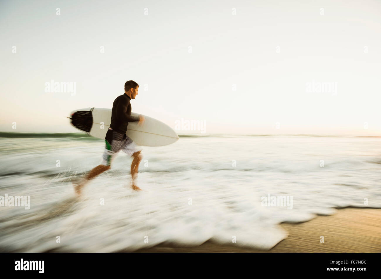 Caucasian man carrying surfboard on beach Stock Photo - Alamy