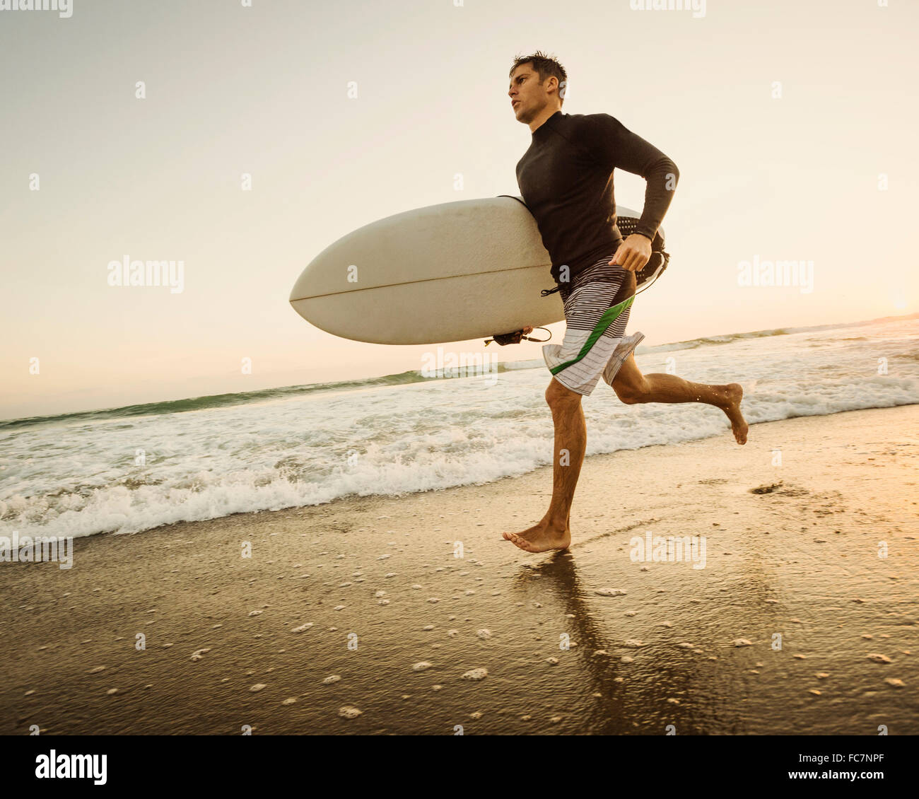 Caucasian man carrying surfboard on beach Stock Photo - Alamy