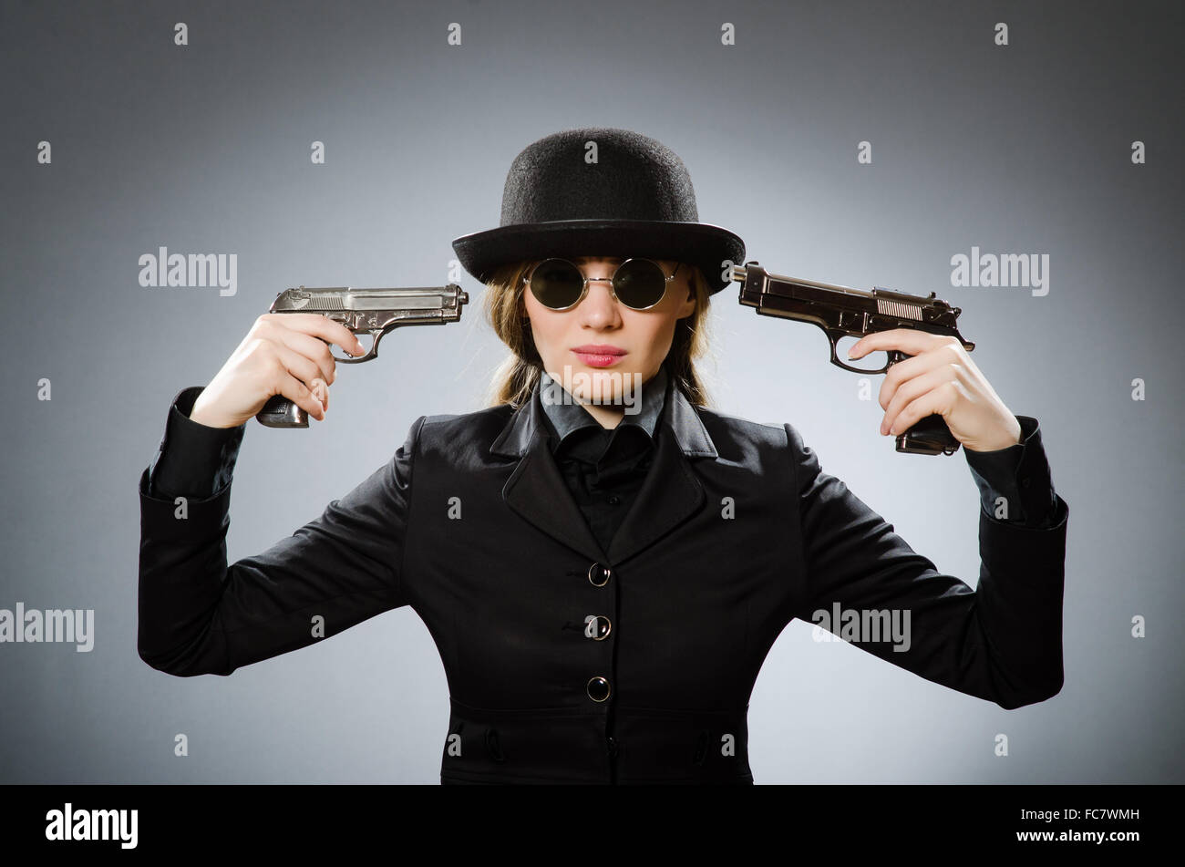 Female spy with weapon against gray Stock Photo - Alamy