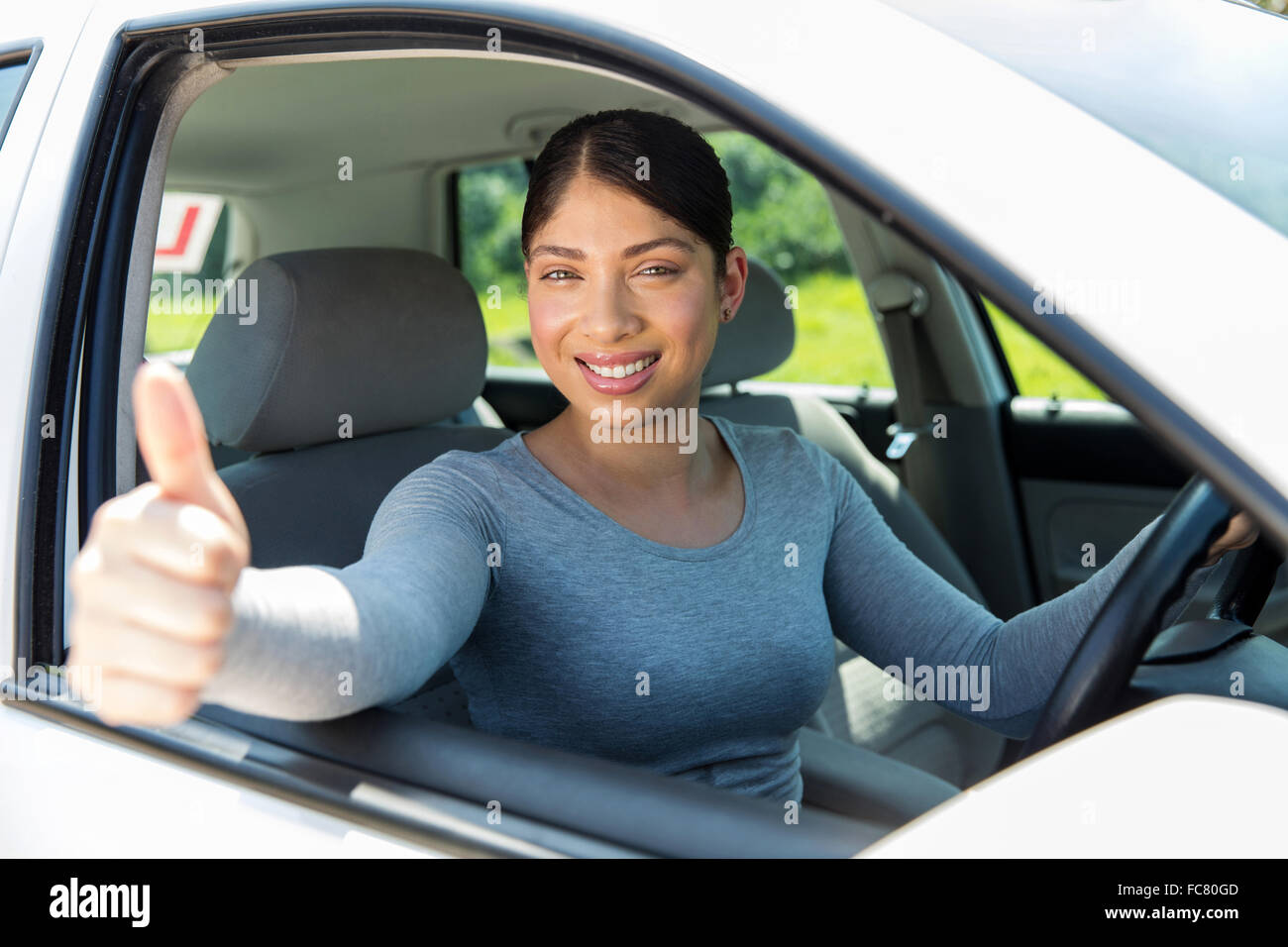 happy young female driver giving thumb up inside a car Stock Photo - Alamy