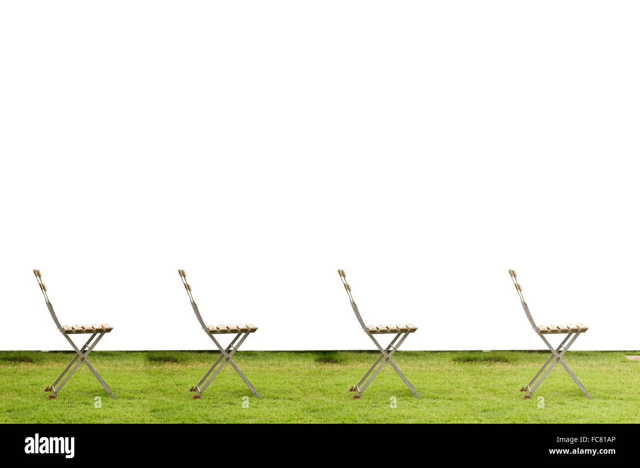 Old chair on green grass in white wall background Stock Photo - Alamy