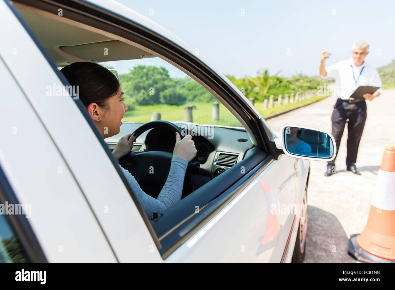 happy young student driver with driving instructor learning to park a ...
