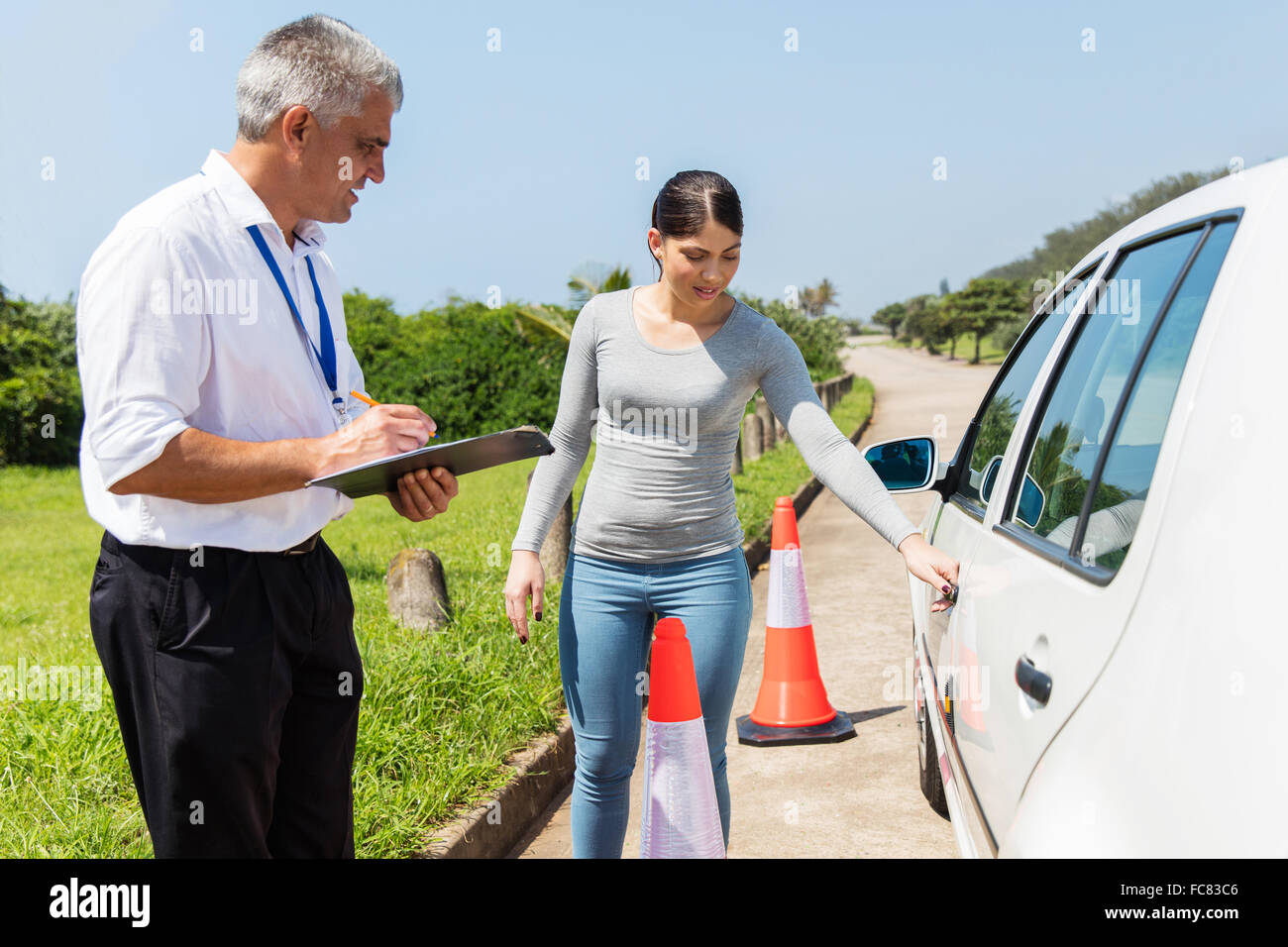 confident female learner driver with instructor doing pre driving ...