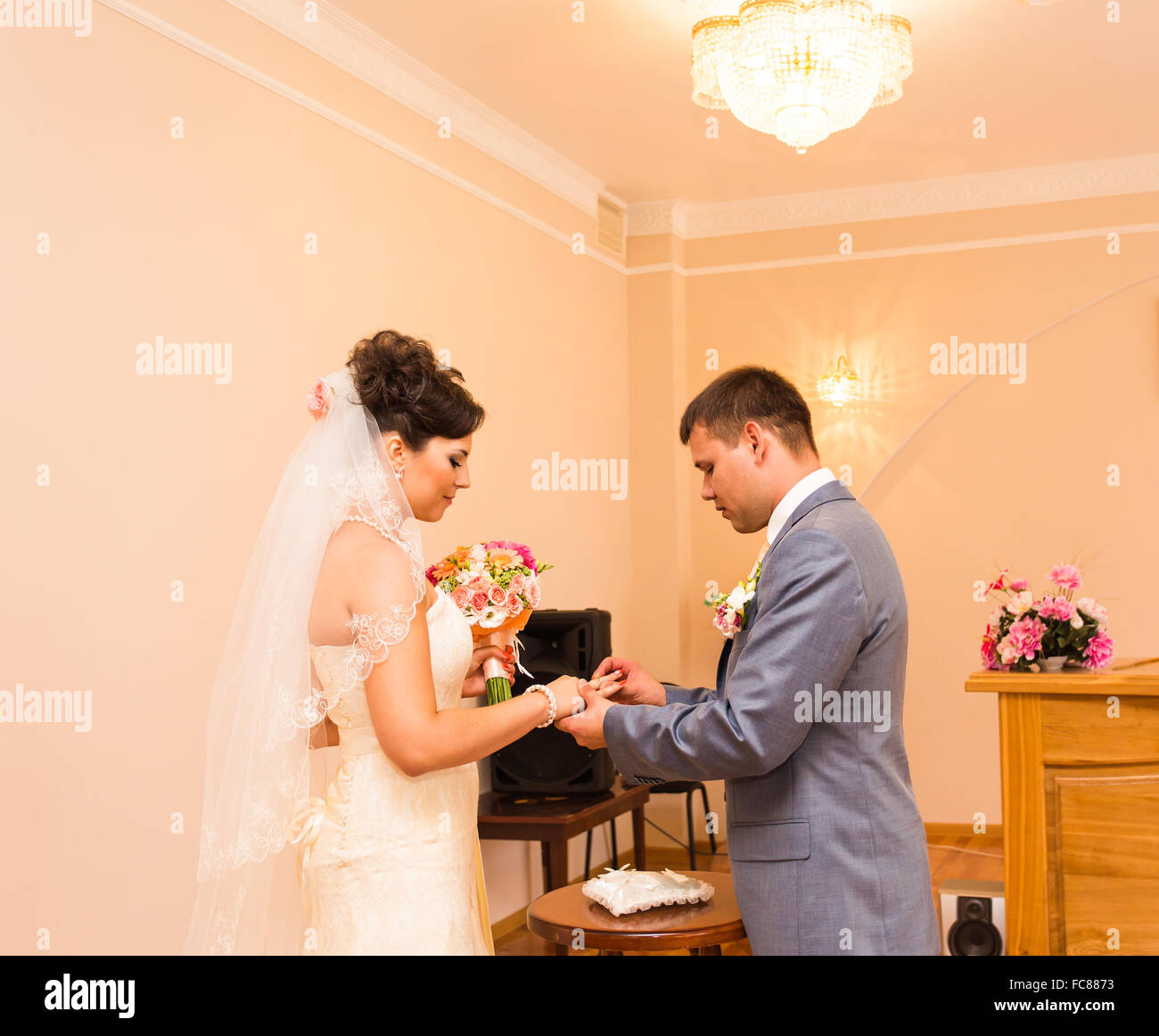 Groom slipping ring on finger of bride at wedding Stock Photo - Alamy