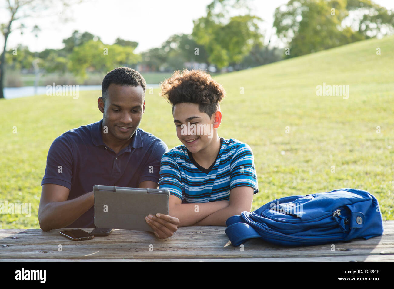 Father and son using digital tablet in park Stock Photo - Alamy