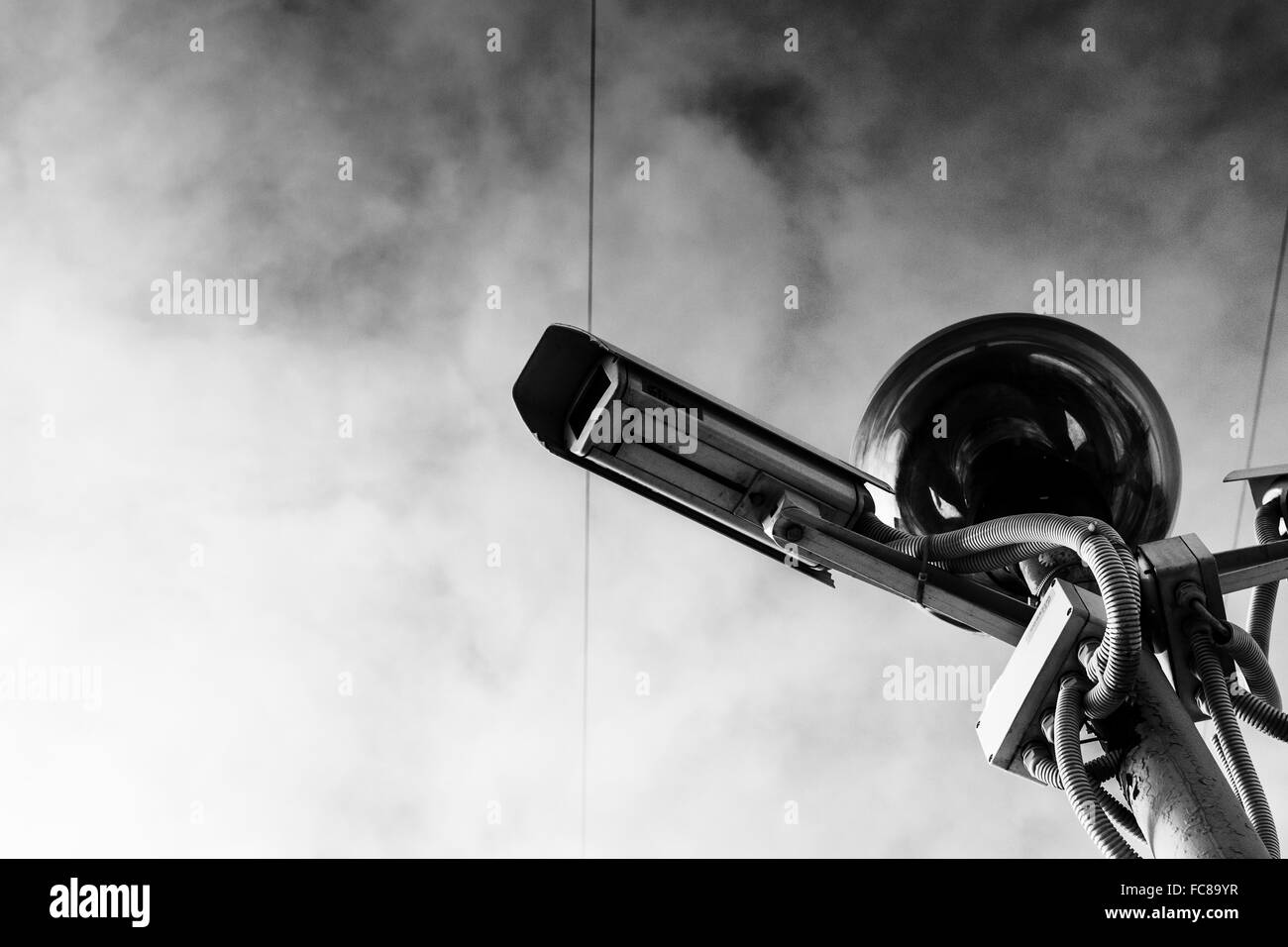 Close-up of a tall CCTV camera and street light in black and white set ...