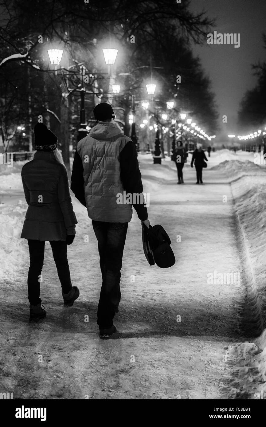 Young couple walk along an illuminated footpath at night with ornate ...