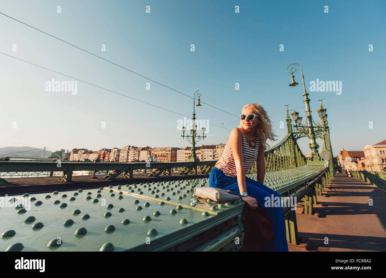 Caucasian woman sitting on bridge Stock Photo - Alamy