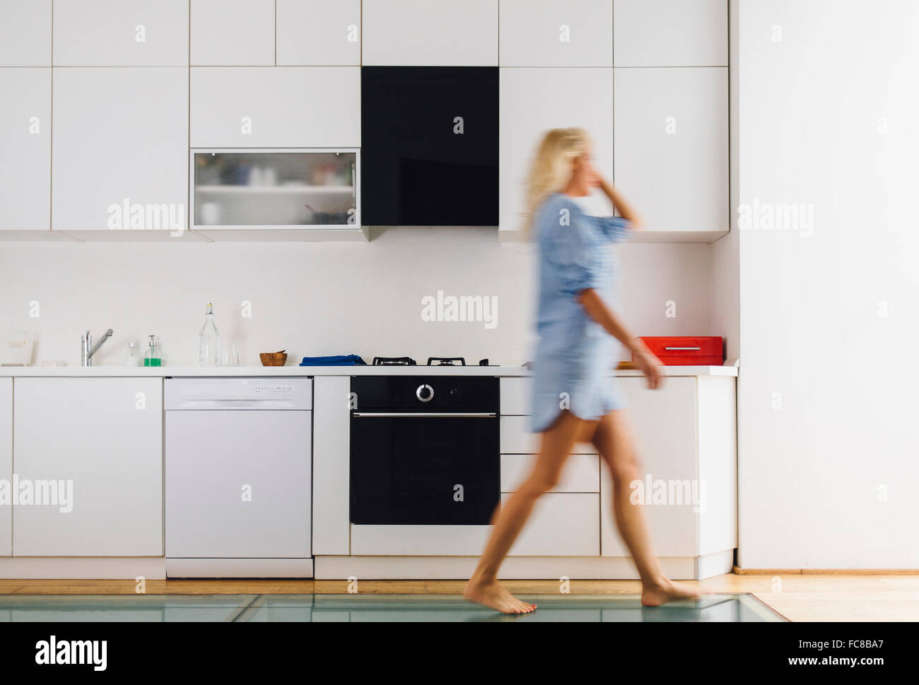 Woman walking in modern kitchen Stock Photo - Alamy