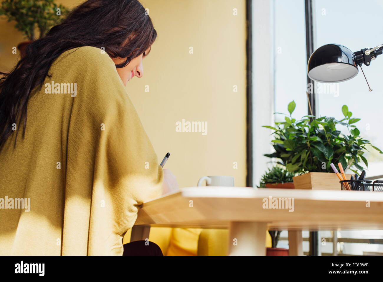 Caucasian woman writing at desk Stock Photo - Alamy