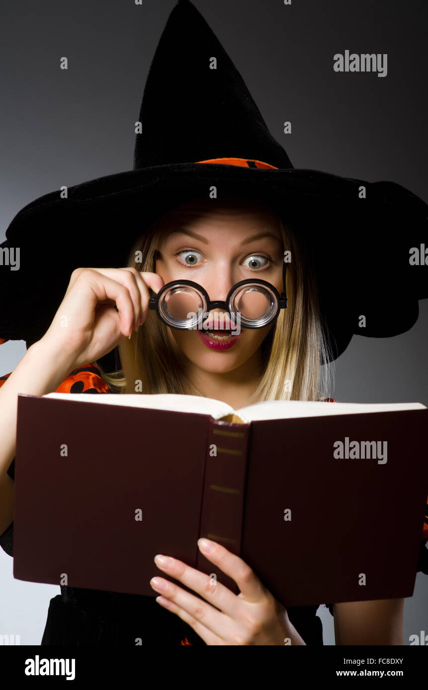 Witch with book in dark studio Stock Photo - Alamy