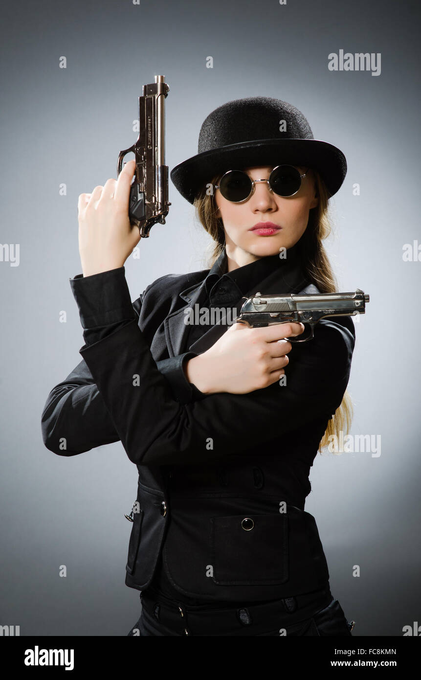 Female spy with weapon against gray Stock Photo - Alamy