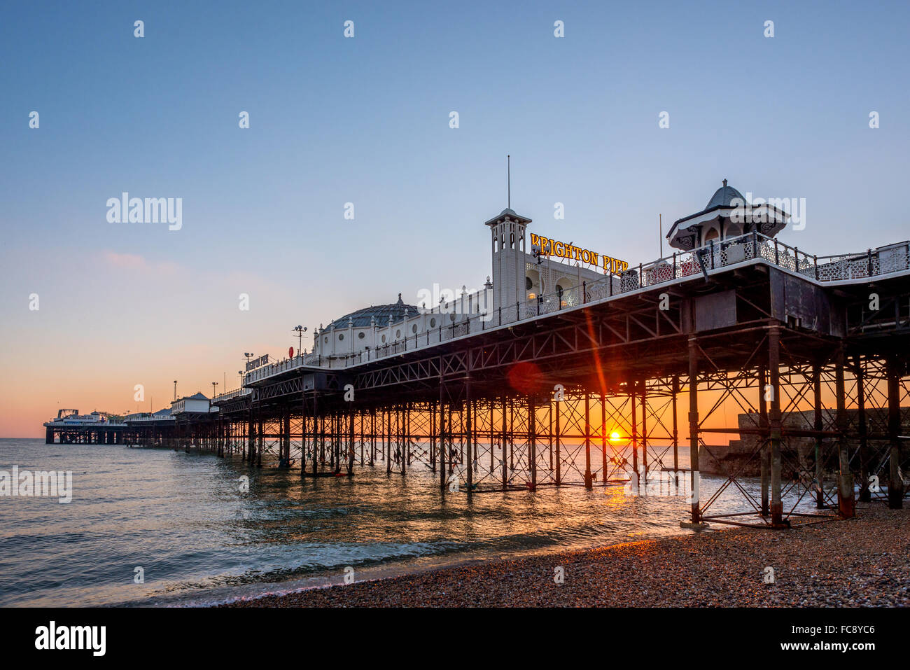 The sun sets on the horizon behind the Palace Pier, Brighton Stock ...