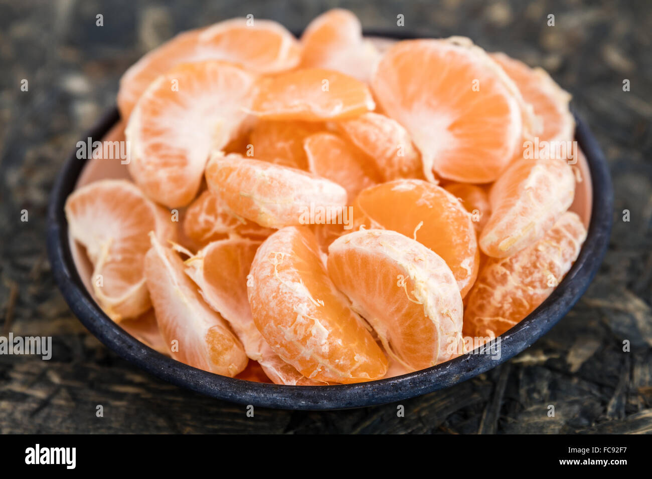 Ripe juicy mandarin fruits in enamel plate on blue wooden background ...