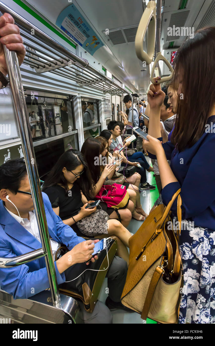 Smartly dressed commuters on the busy subway looking at their phones ...