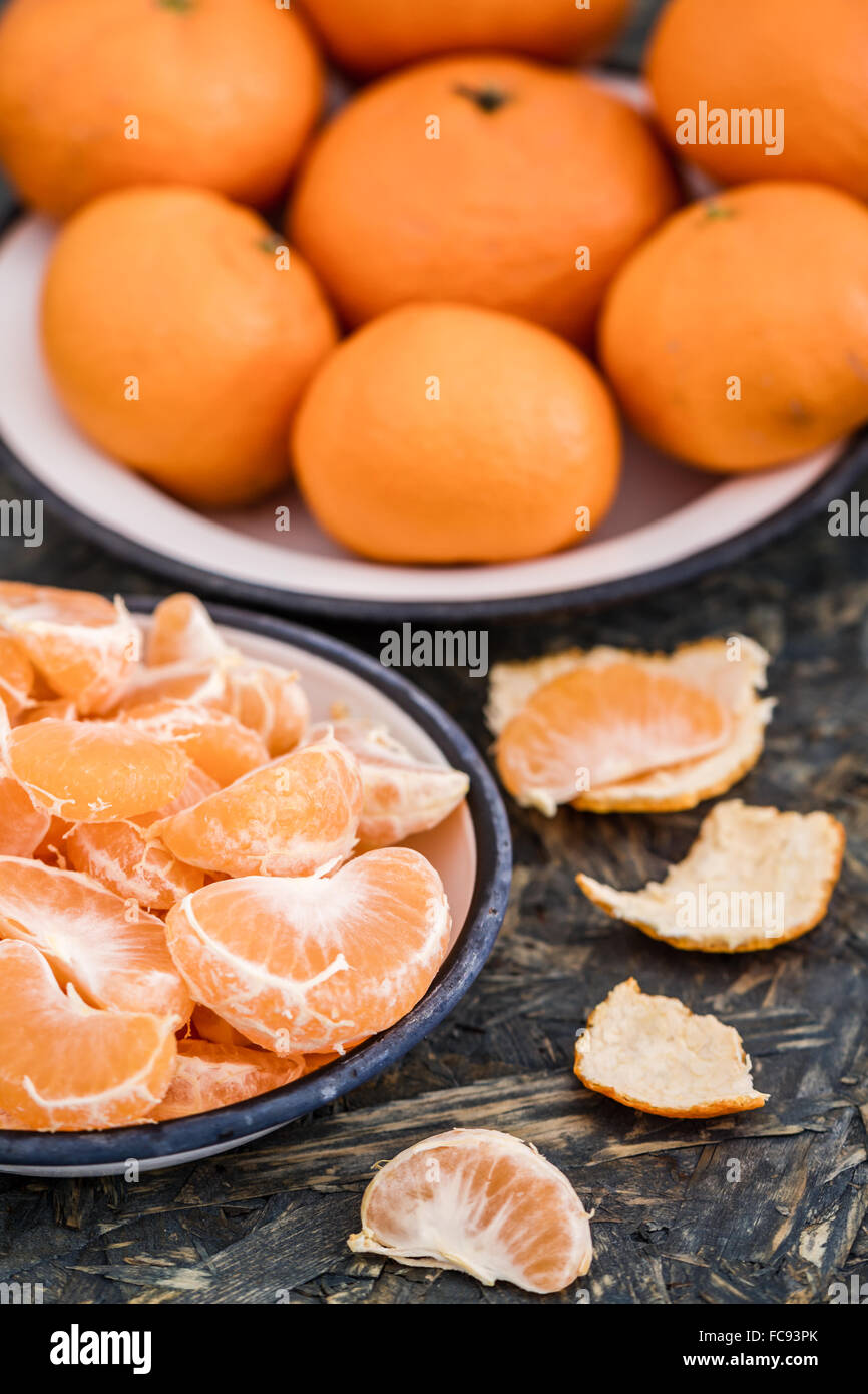 Ripe juicy mandarin fruits in enamel plates on blue wooden background ...