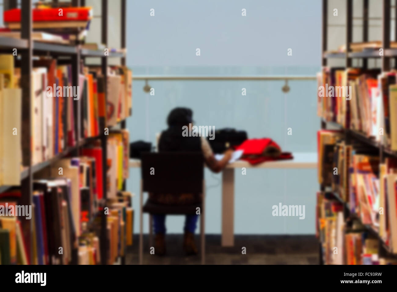 Blurred books and student studying in a library Stock Photo - Alamy
