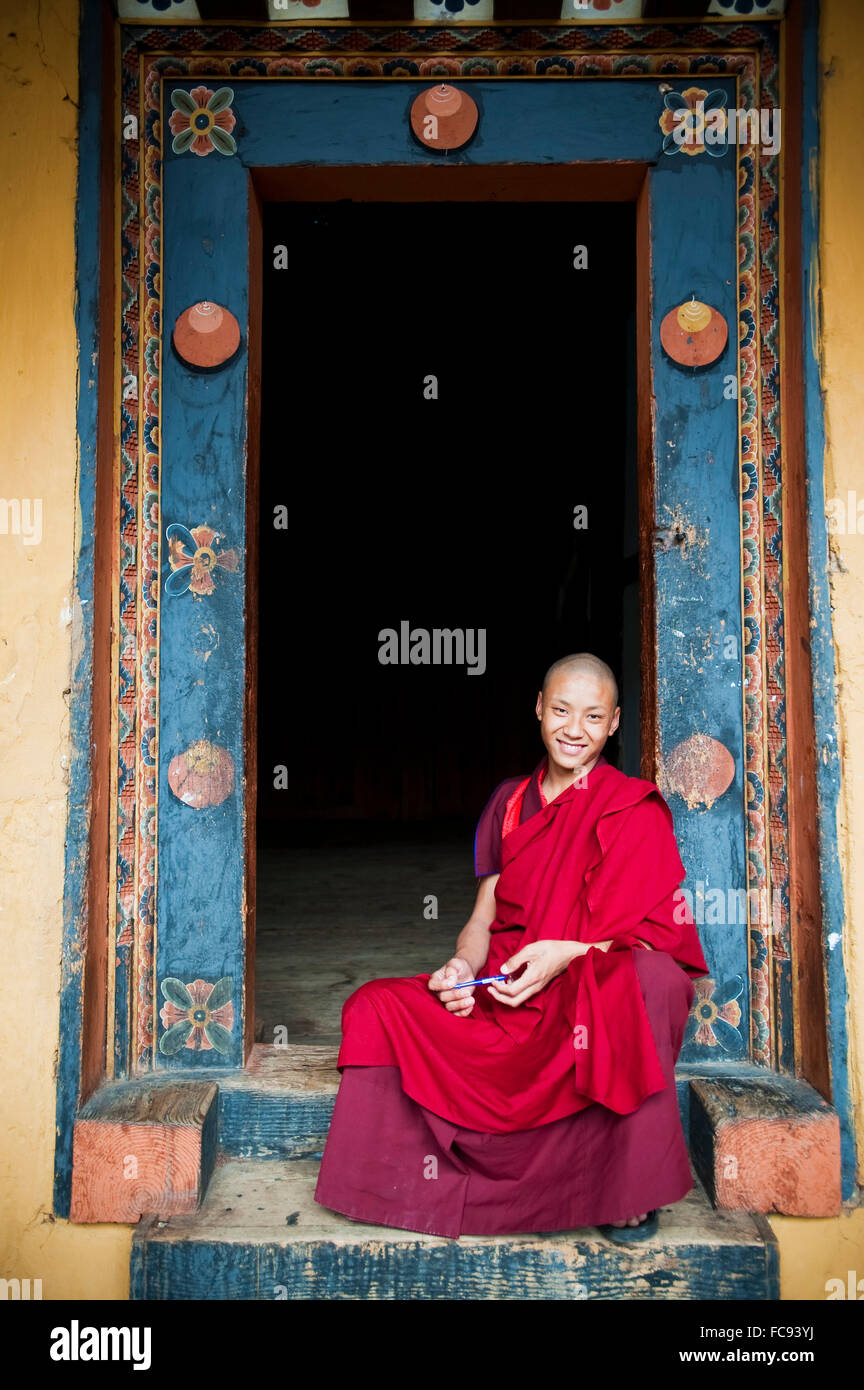 Young monk sitting in an ornate doorway, Punakha, Bhutan, Asia Stock ...