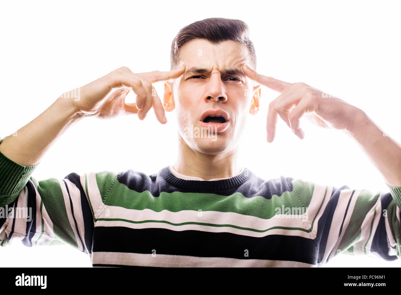 Portrait of a smart serious young man standing against white background ...