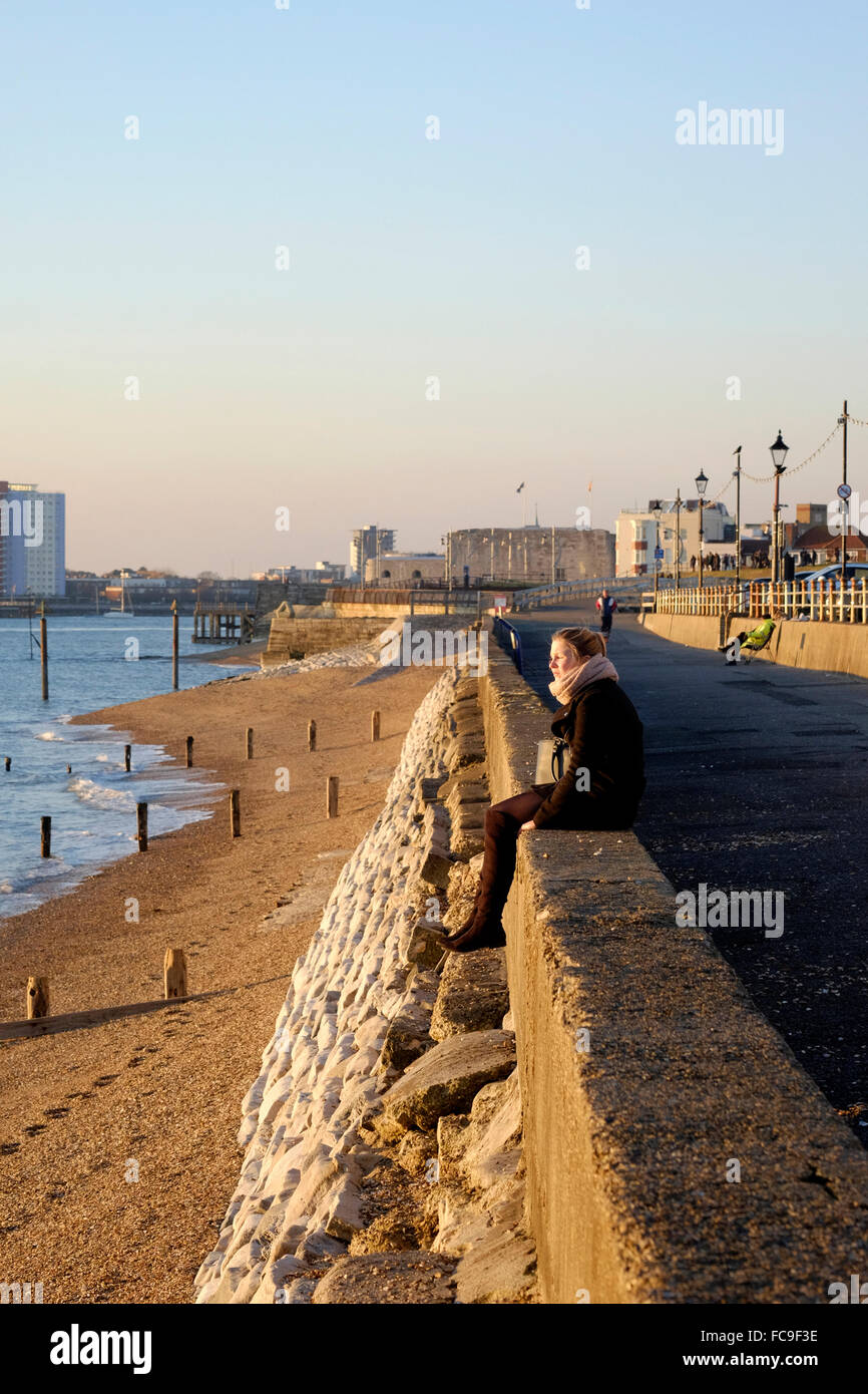 young woman sat in the golden light of sunset on southsea seafront ...