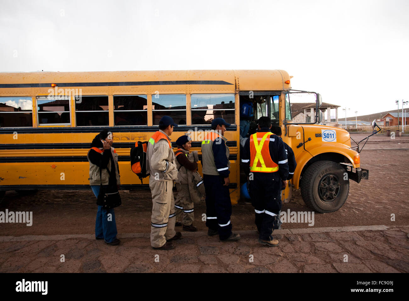 A group of miners line up to board a school bus in a small town in ...