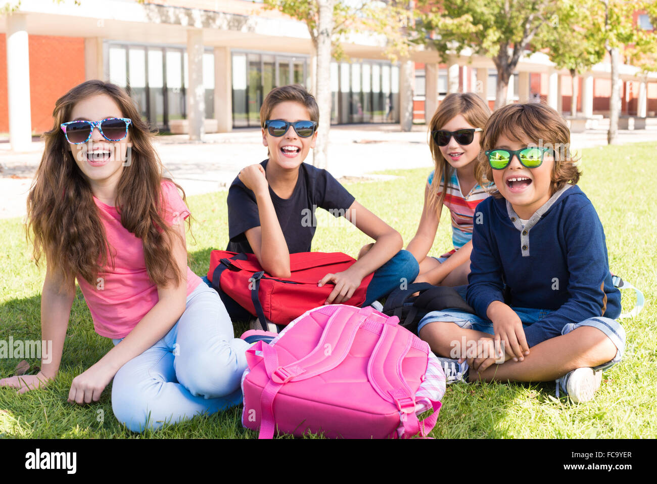 Group of little students sitting on the grass at school Stock Photo - Alamy