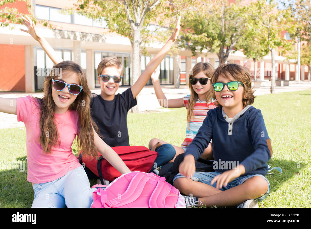 Group of little students sitting on the grass at school Stock Photo - Alamy