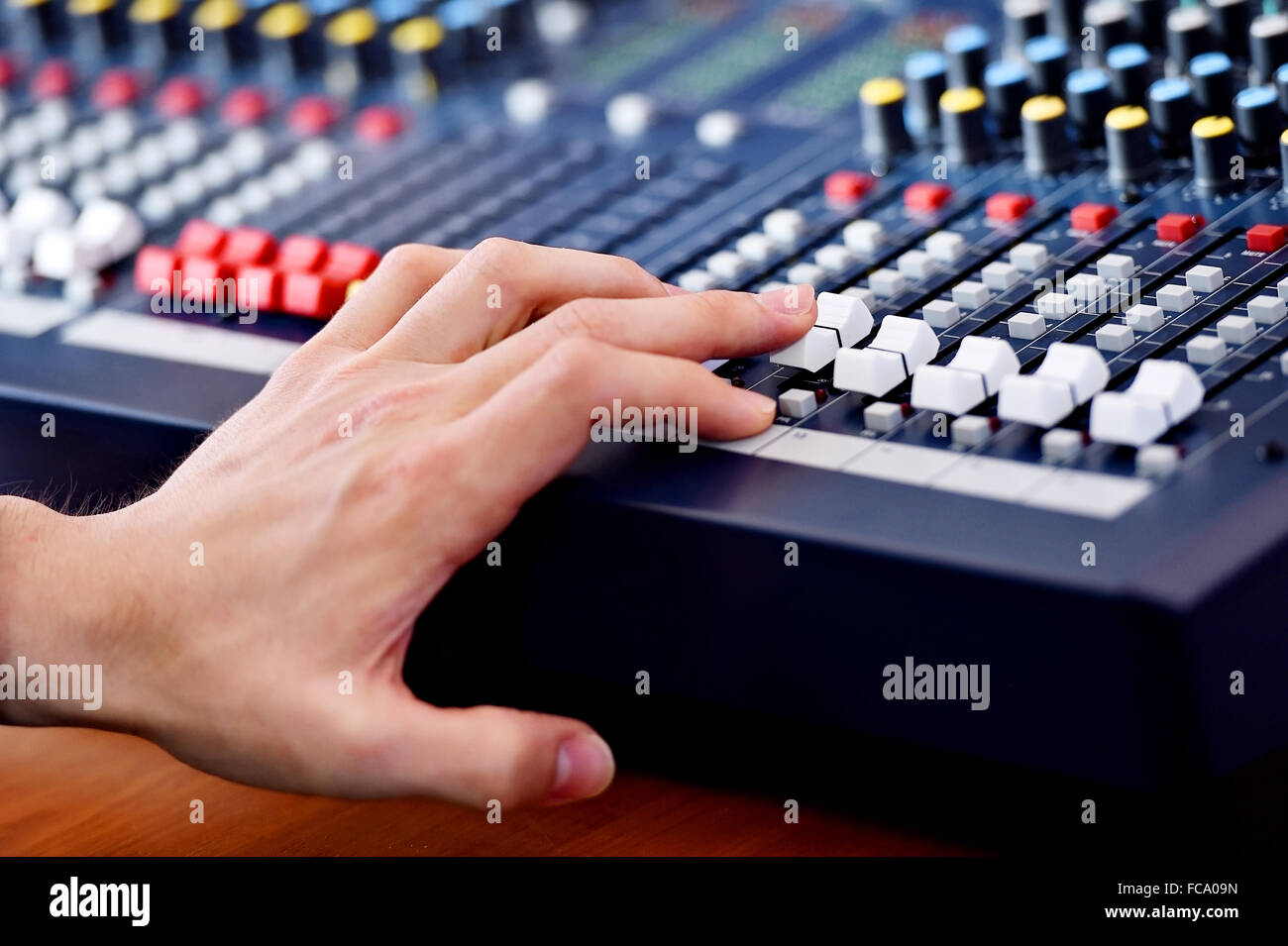 Detail with a hand adjusting sound levels on a professional audio mixer ...