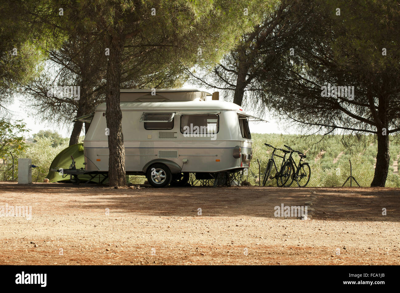 Small white caravan through the trees Stock Photo - Alamy