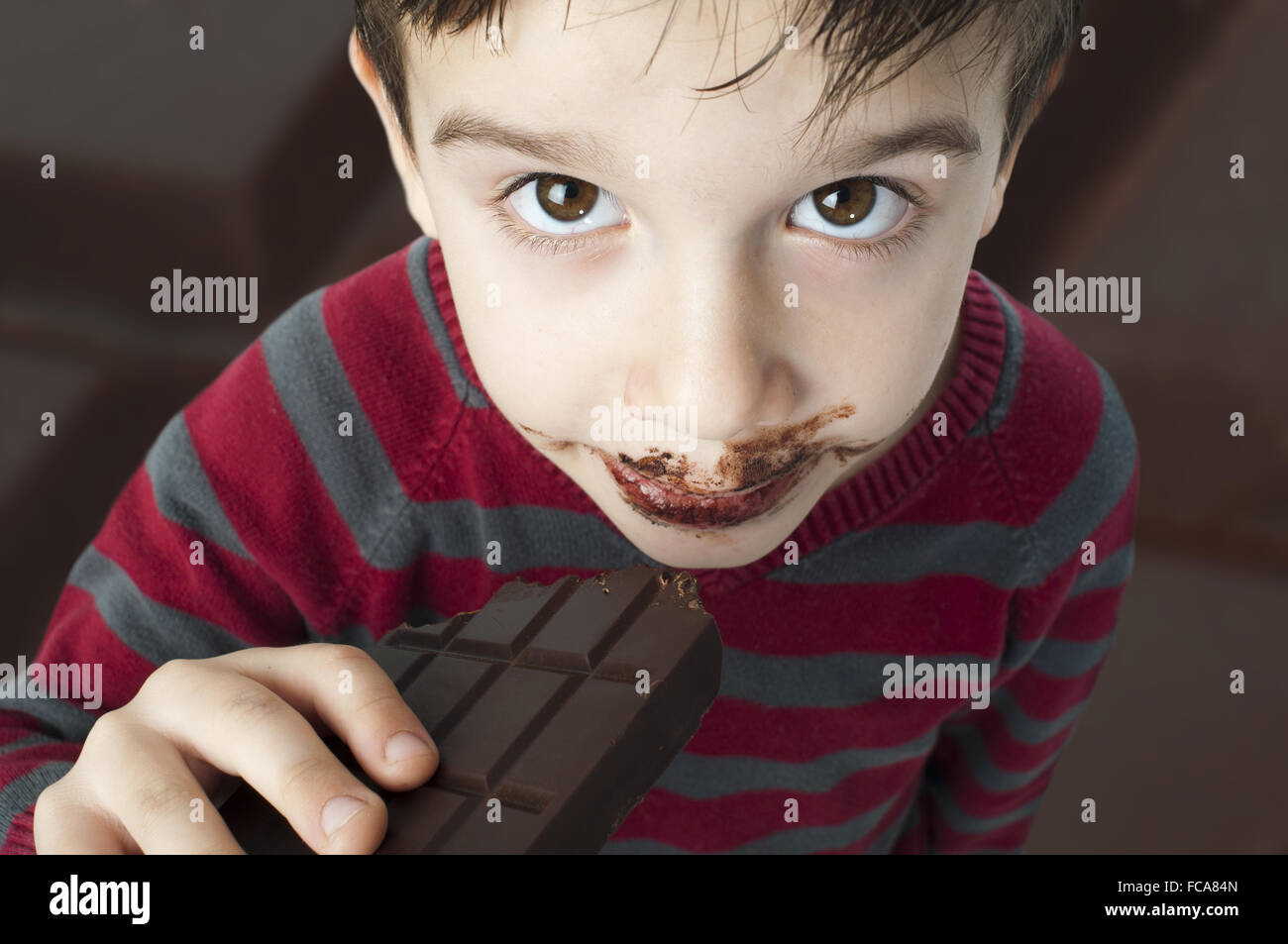 Smiling little boy eating chocolate Stock Photo - Alamy