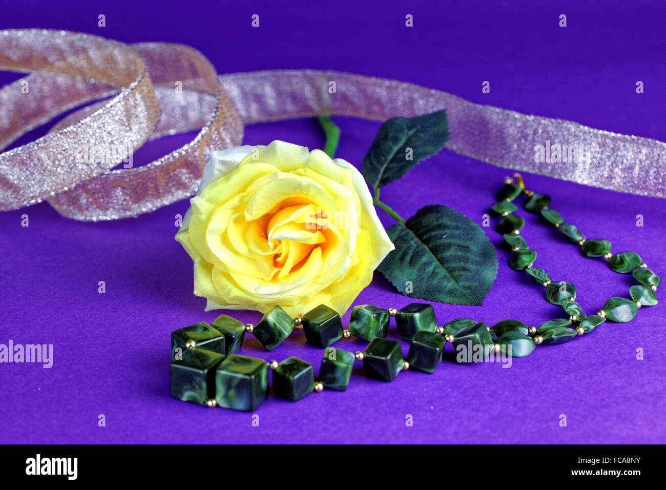 Single yellow rose with ribbon on purple background Stock Photo - Alamy