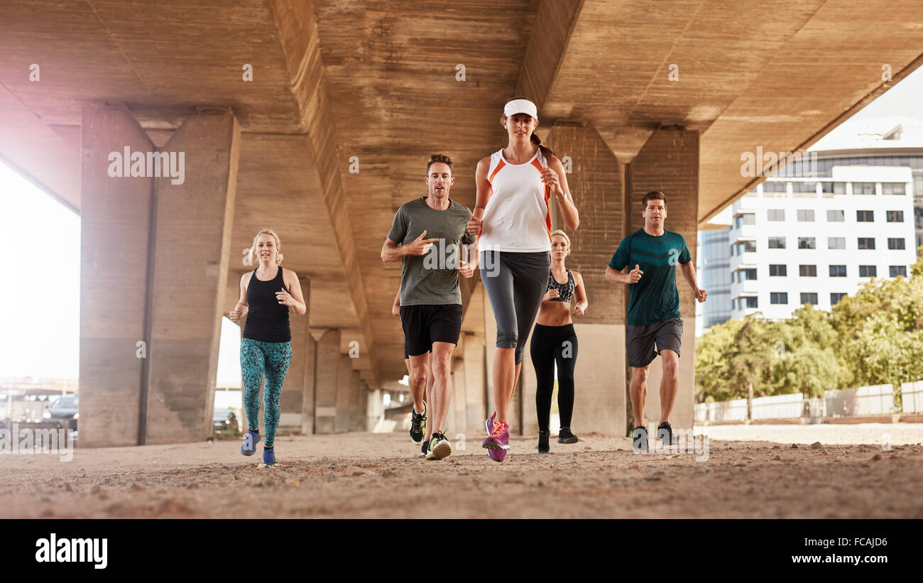 Portrait of group of young people in sports clothing running under a ...