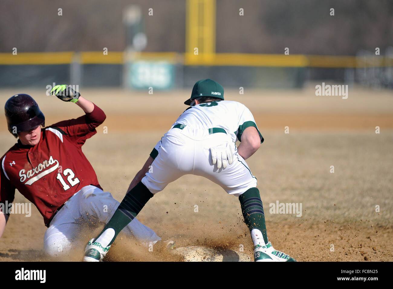 A high school base runner slides safely into third base after advancing ...