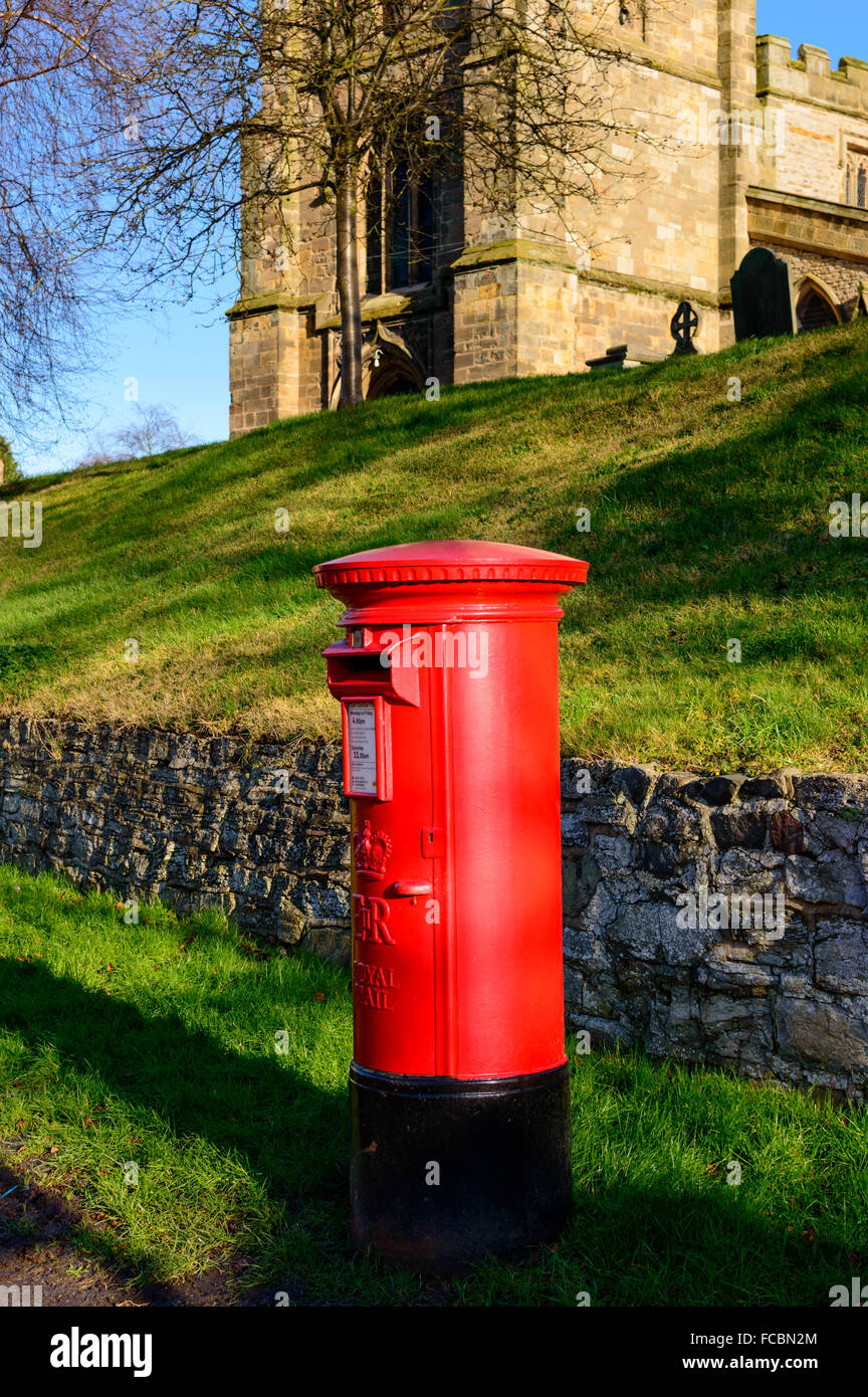 A rural British red traditional Royal Mail pillar box. With St Mary's ...