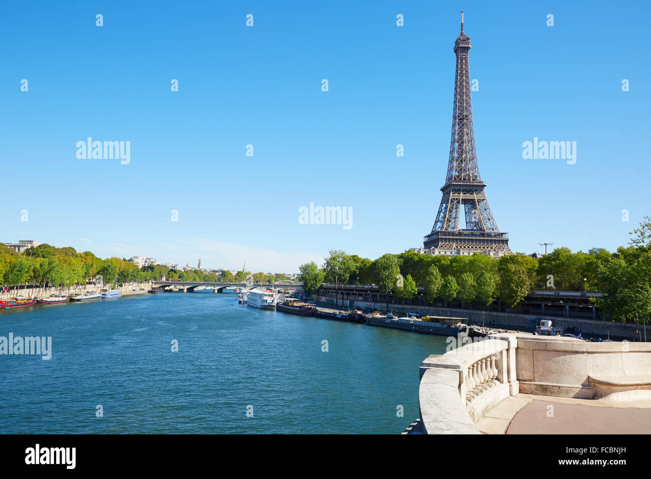 Eiffel tower and empty white balustrade on Seine river in a clear sunny ...