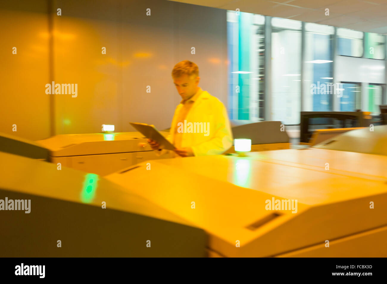 Worker with clipboard walking along printers in printing plant Stock ...