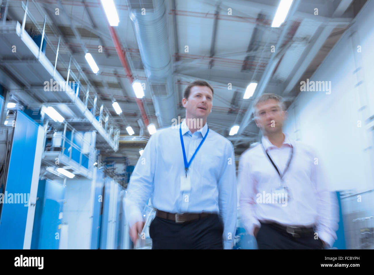 Businessmen walking in factory Stock Photo - Alamy
