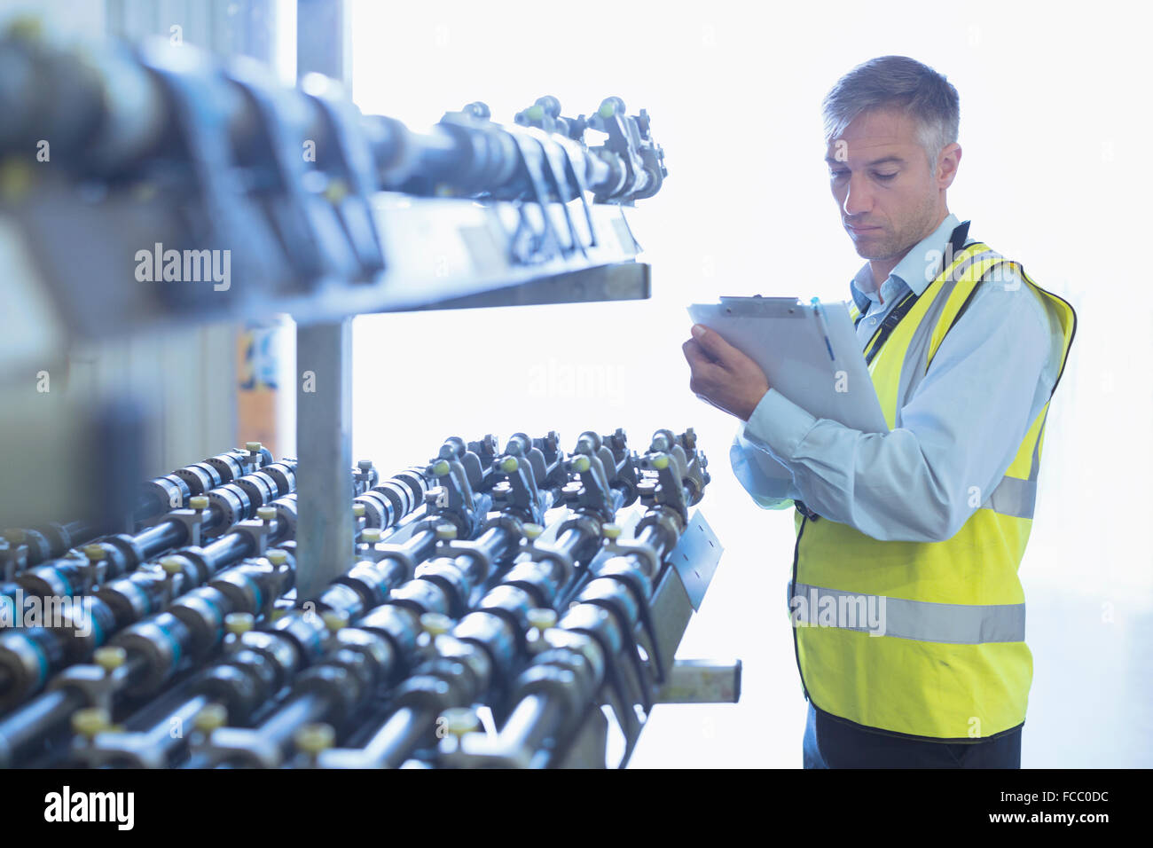 Engineer with clipboard checking printing press conveyor belt Stock ...