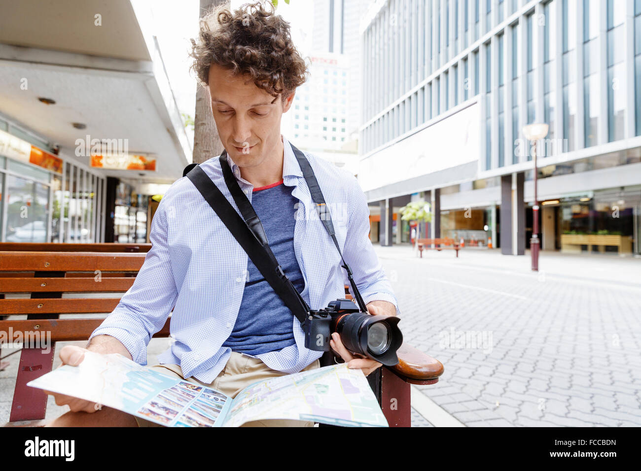 Happy male tourist in city with camera and map Stock Photo - Alamy